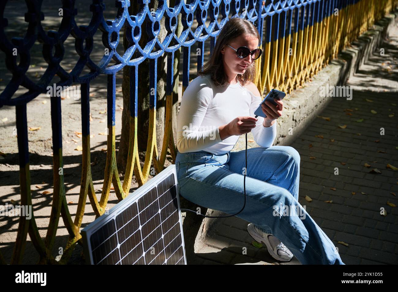 Happy woman connecting smartphone to photovoltaic solar panel ...