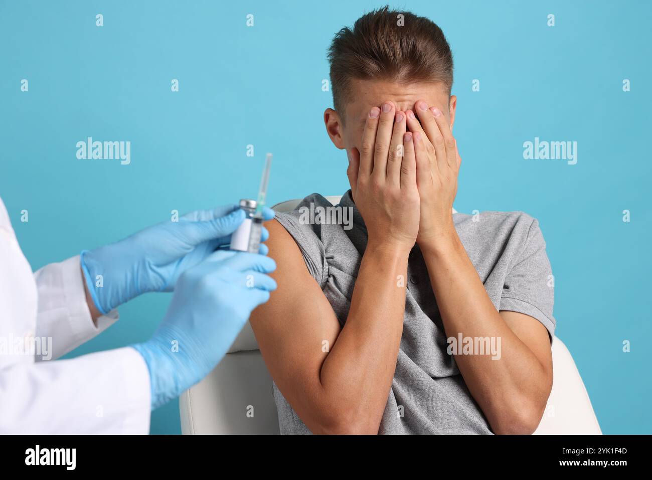 Needle phobia. Doctor with syringe and vial near scared man on light ...