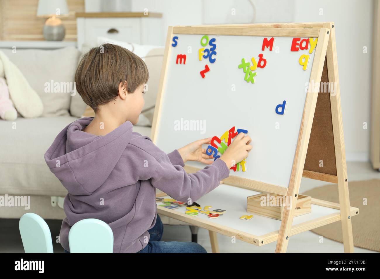 Little boy learning alphabet with magnetic letters indoors Stock Photo ...