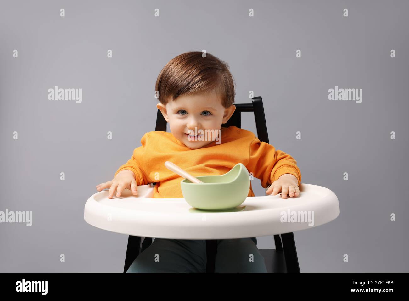 Cute little kid eating healthy baby food from bowl in high chair on ...