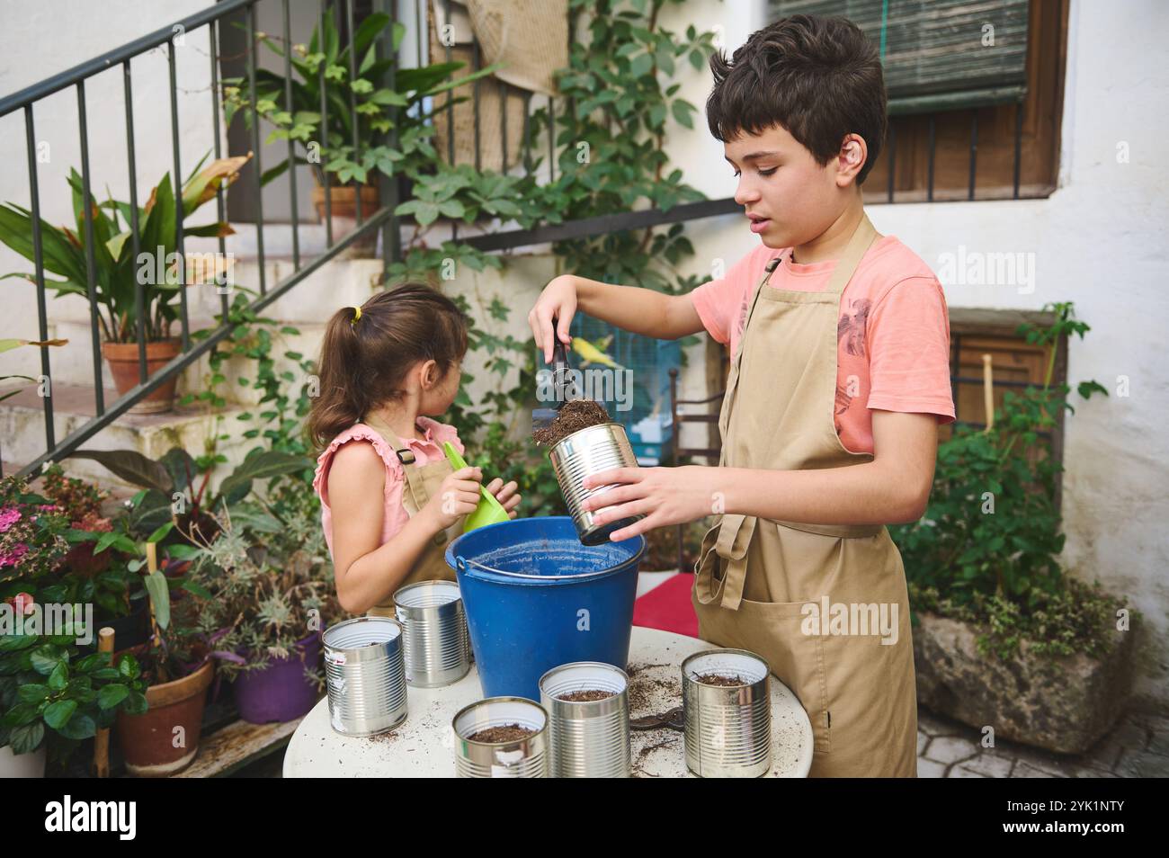 Two children engage in a fun gardening activity, using recycled cans as ...