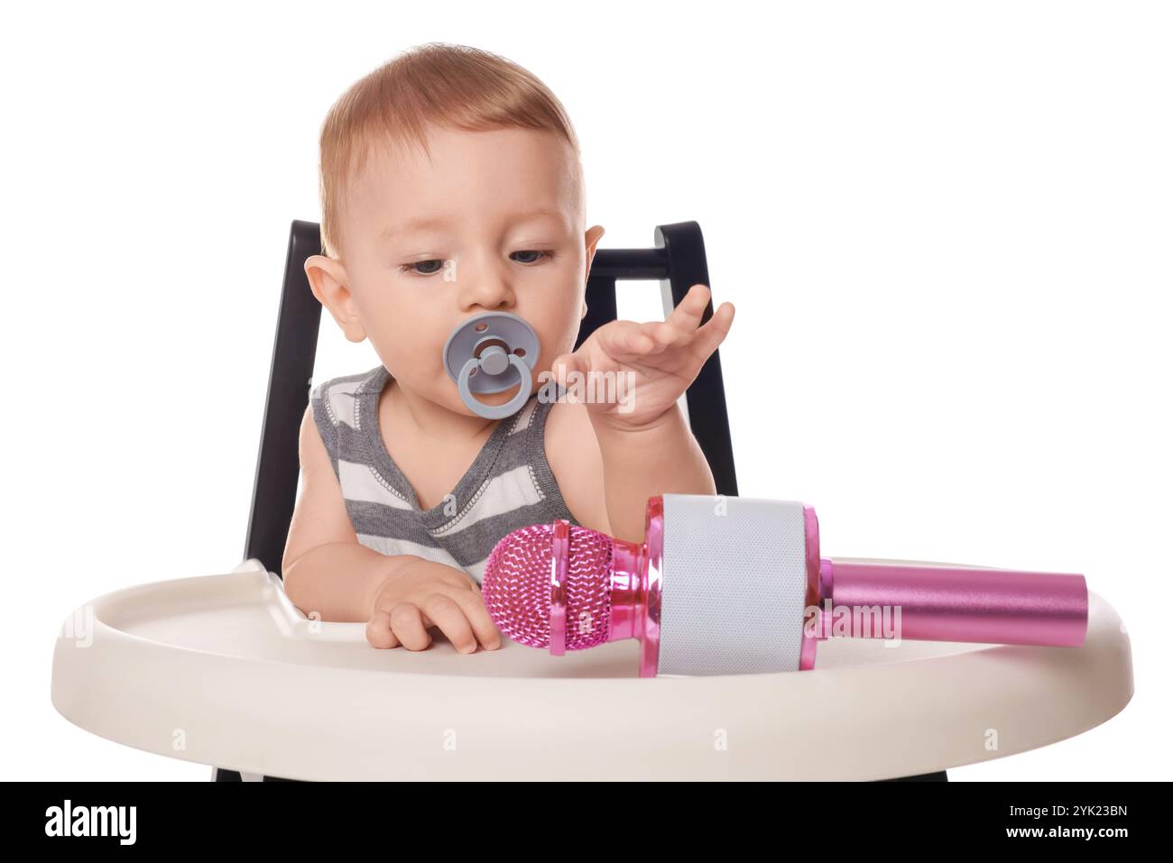 Cute little baby with pacifier and microphone in high chair on white ...