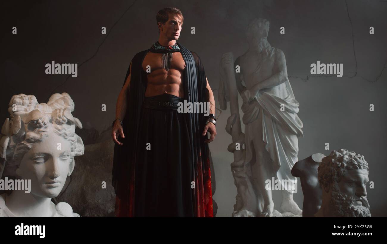 Muscular charismatic bodybuilder model in a silk cape makes an ...