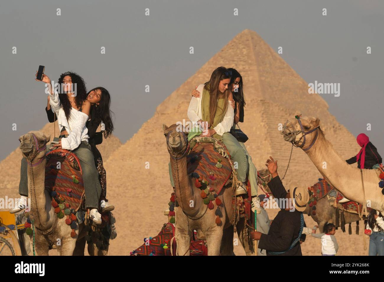 Visitors pose for pictures on camels at the historical site of Giza Pyramids, on the outskirts ...