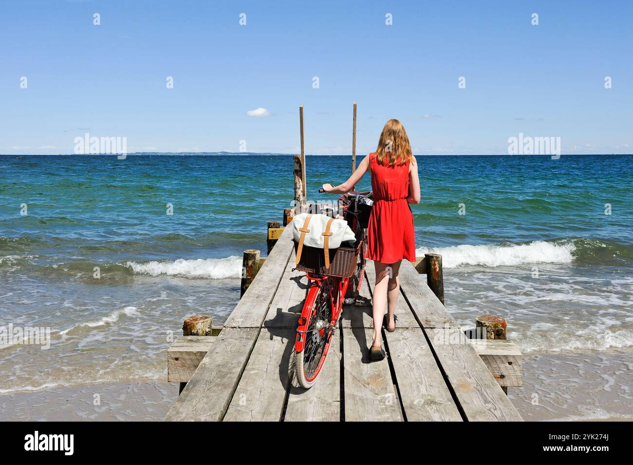 Red dressed woman with a bike on a pontoon on Moesgaard Beach, Aarhus ...