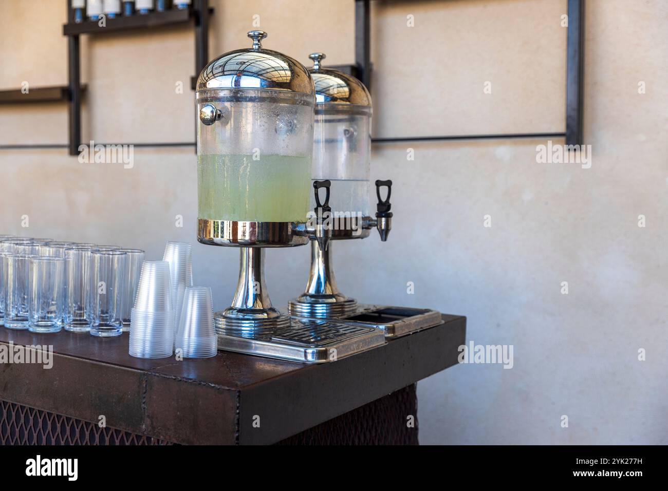 Lemonade in a pitcher with a spout and plastic cups on the table in a ...