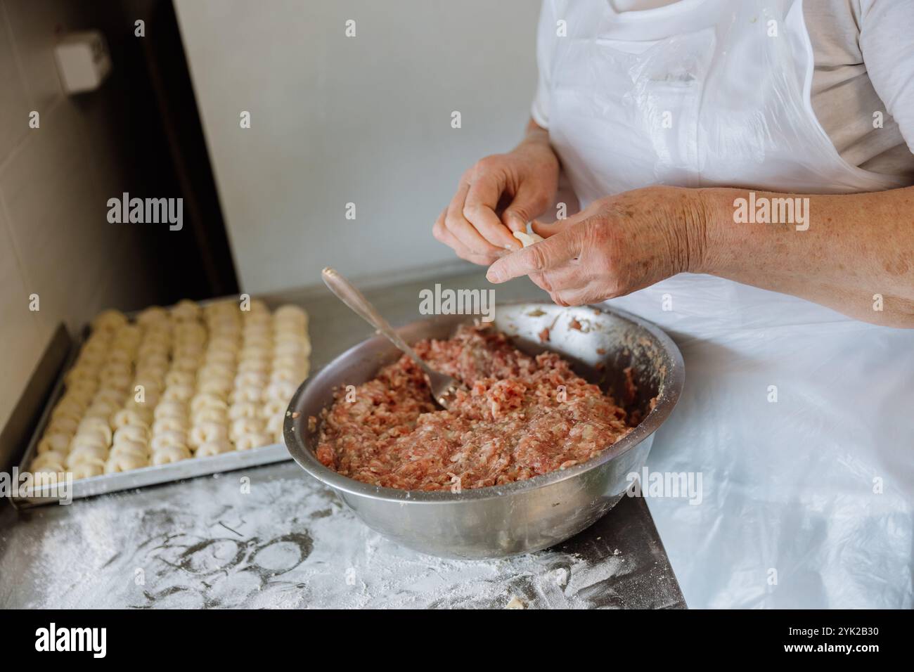 Hands making traditional dumplings with fresh meat filling in a home ...