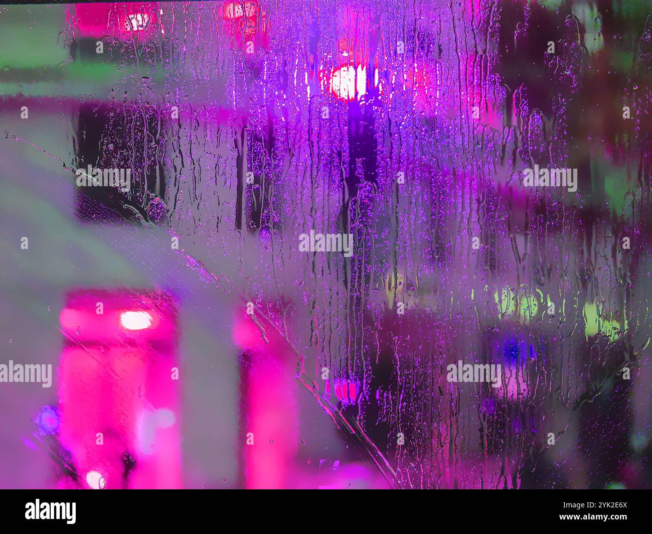 Pink neon urban city lights behind the rainy window with raindrops in ...