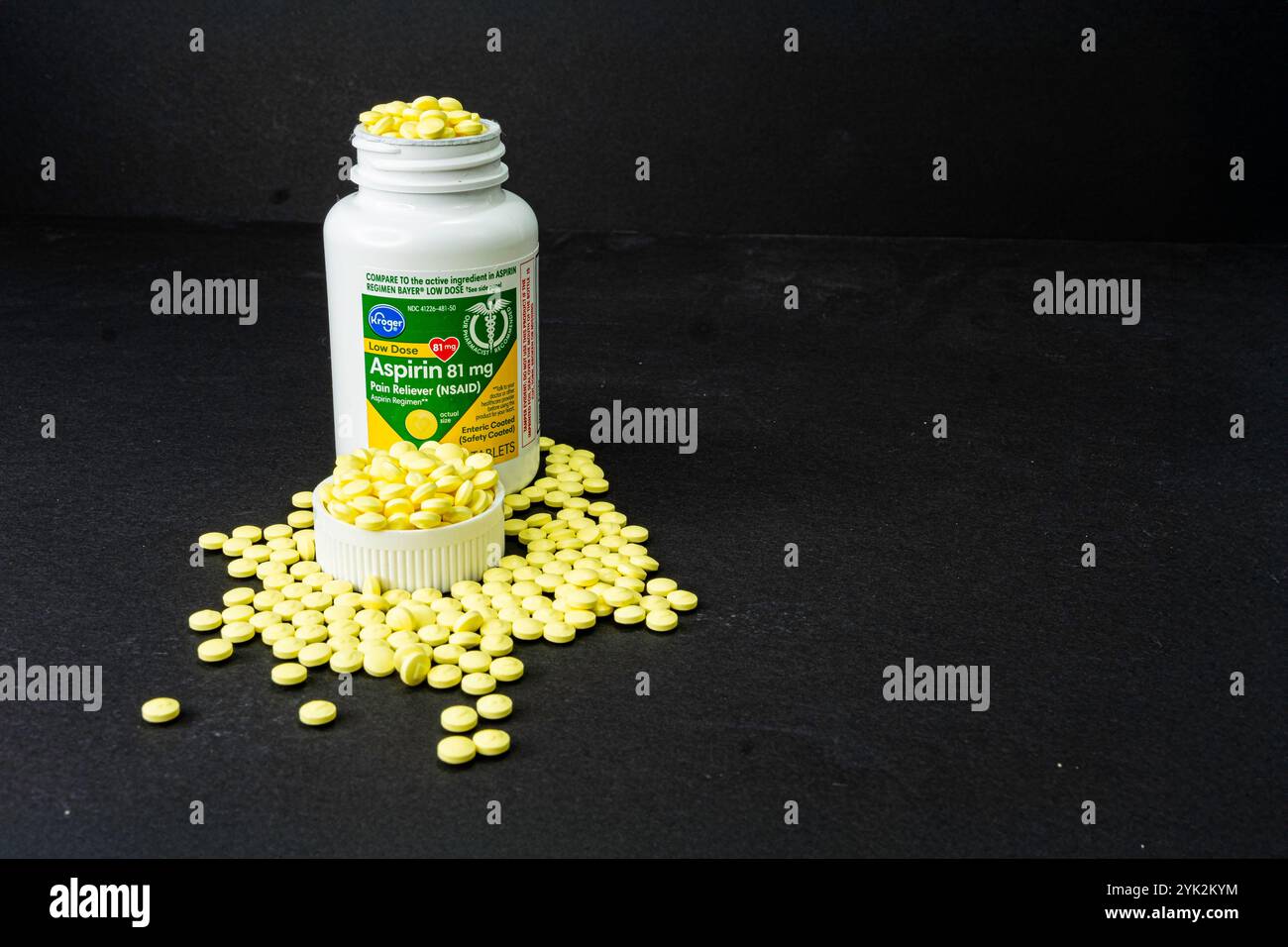 Baby Aspirin overflowing out of their container. A lot of yellow pill ...