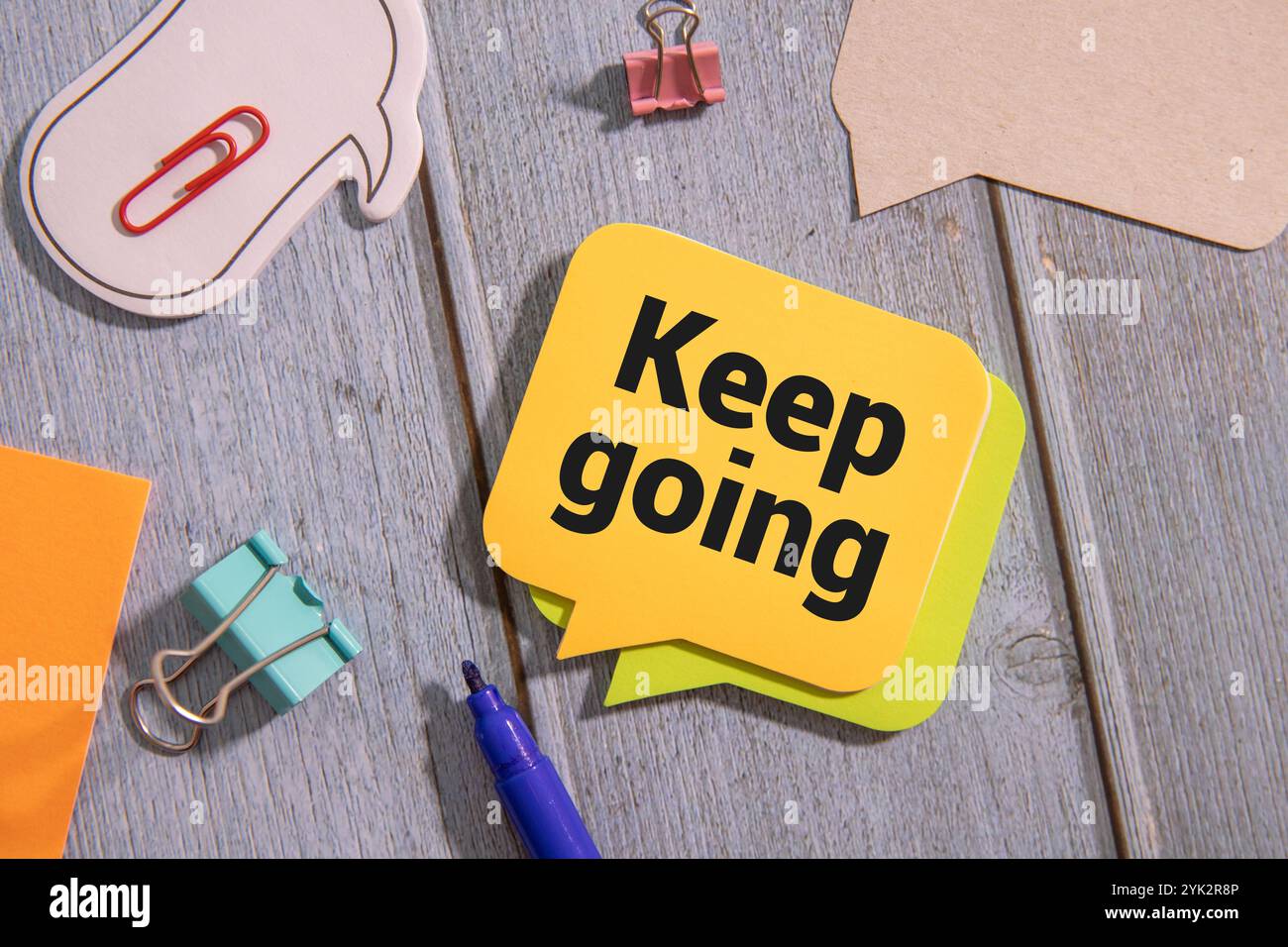 Keep going. Woman holds a white page with text "Keep going" in black ...