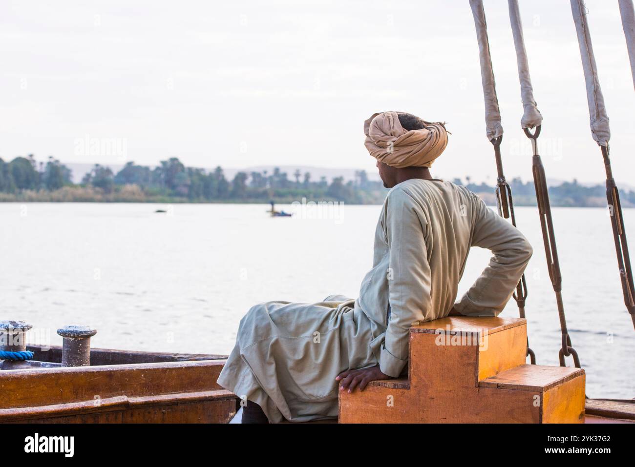 Member of the crew sitting at the prow of a dahabeah, passenger river ...