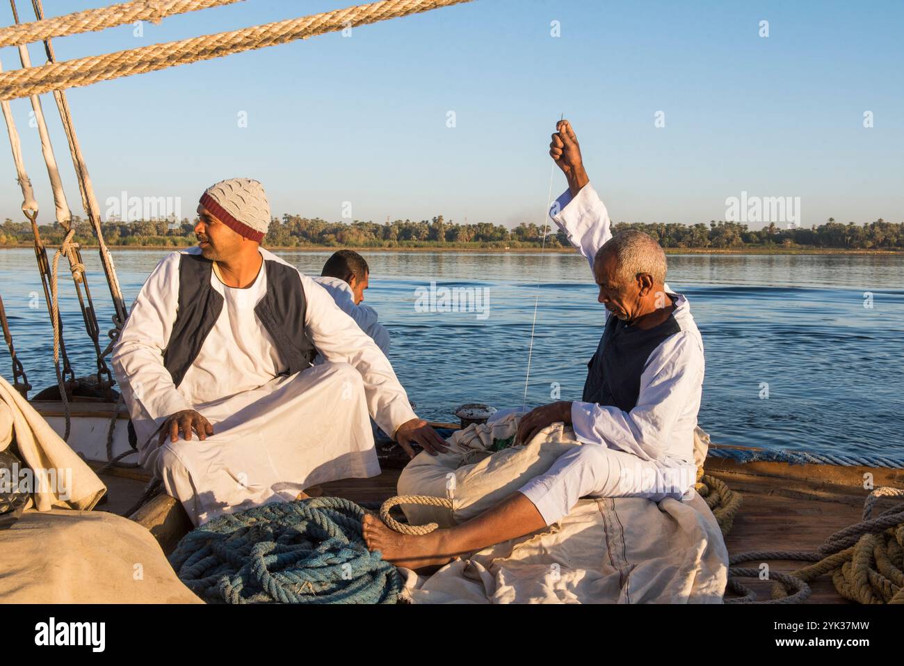 Members of the crew sitting at the prow of a dahabeah, passenger river ...