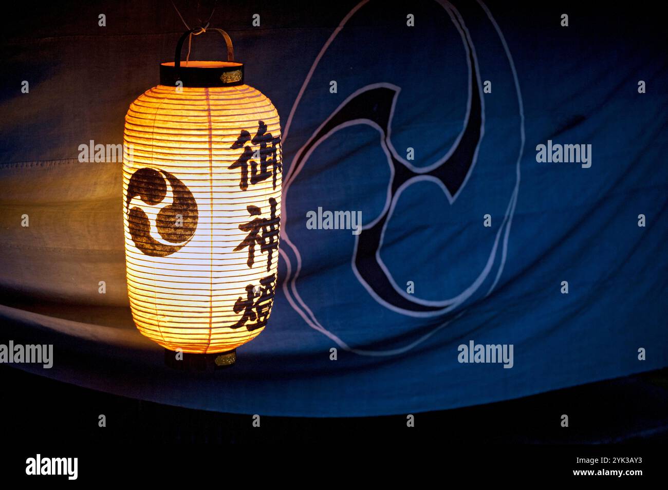 Glowing paper lantern with kanji characters beside a blue drape at the ...