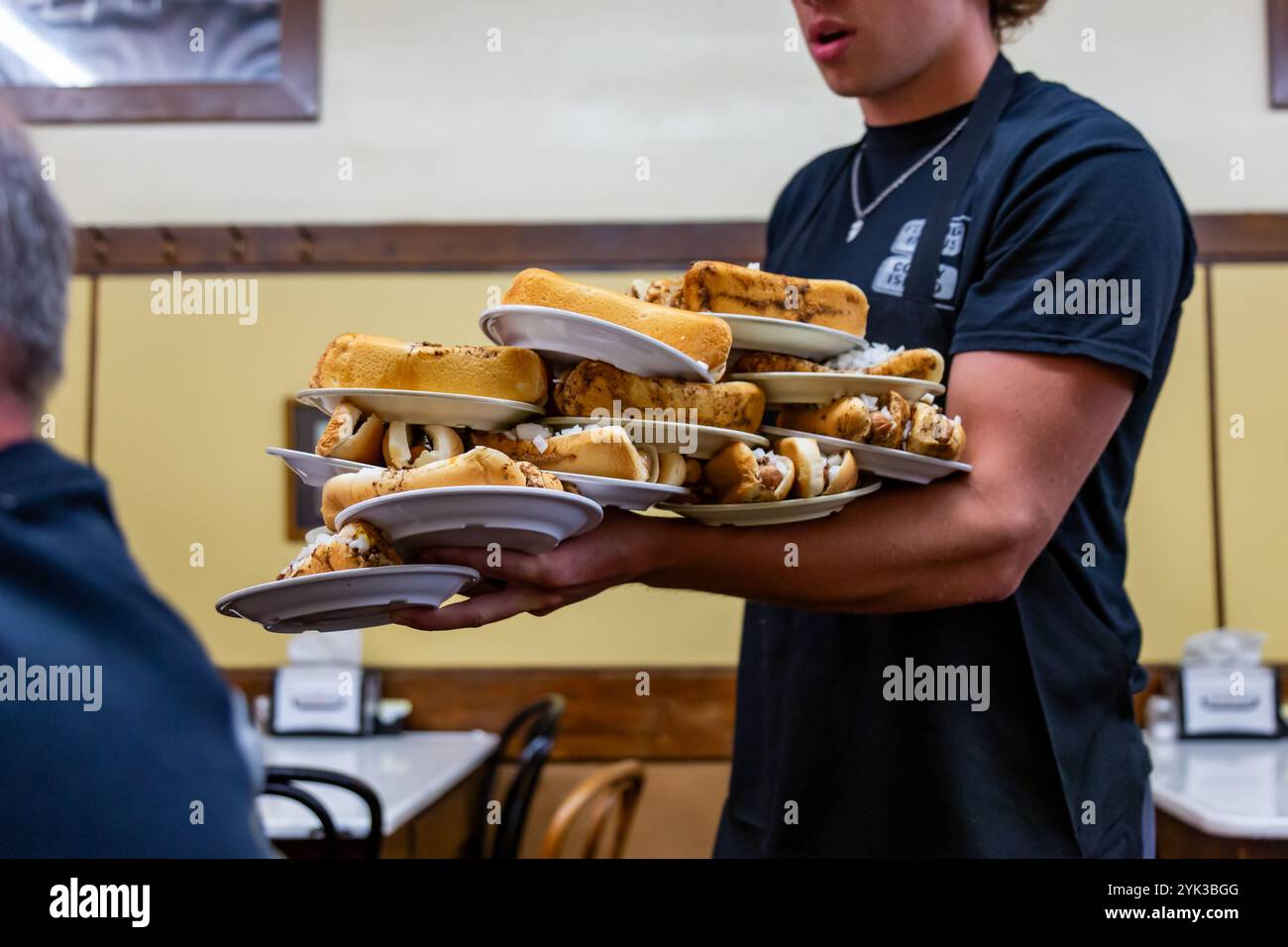 A server balances plates of hot dogs on his arm as he carries them to ...