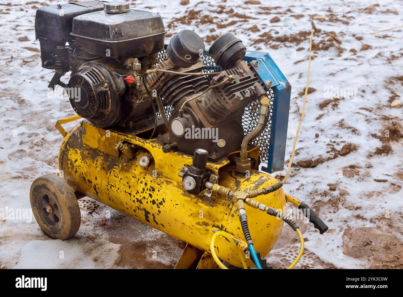 Portable air compressor sits in mud on construction site, with dirt ...