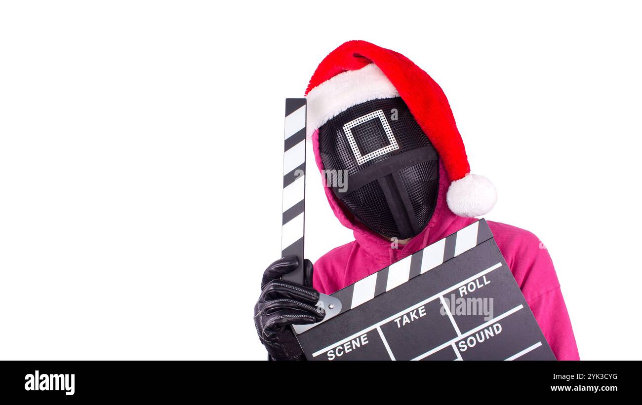 Squid Game pink guard with Christmas hat holding movie clapperboard on ...