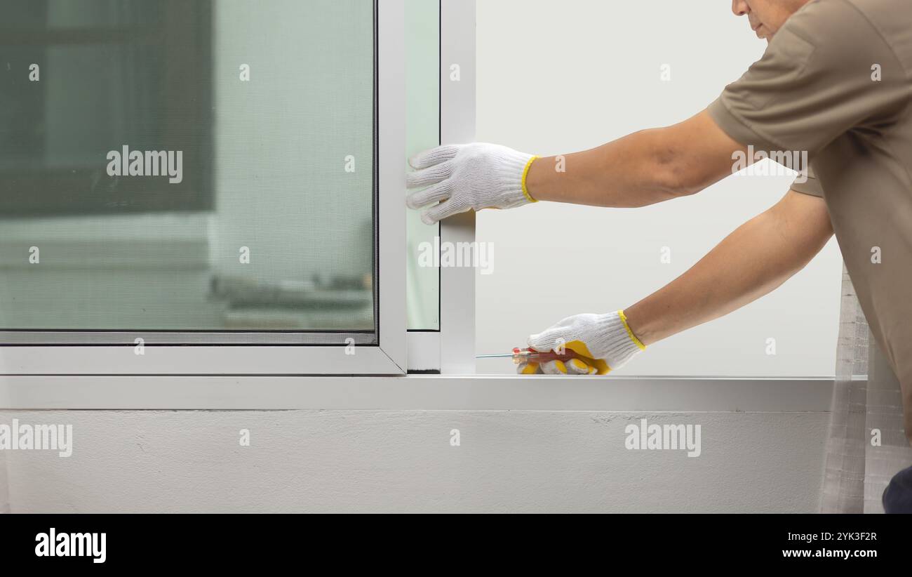 Construction worker repairing the sliding window Stock Photo - Alamy