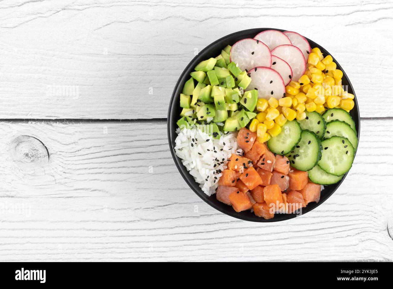 Poke bowl with salmon, rice, cucumber, corn, radish, avocado on a white ...