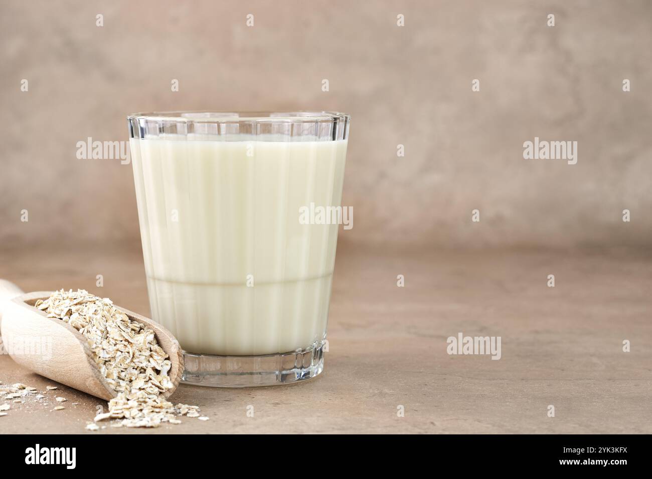 A glass of oat milk and oatmeal on beige background. copy space. The ...