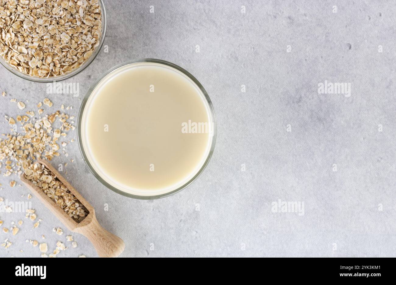 A glass of oat milk and oatmeal on gray background. Top view. The ...