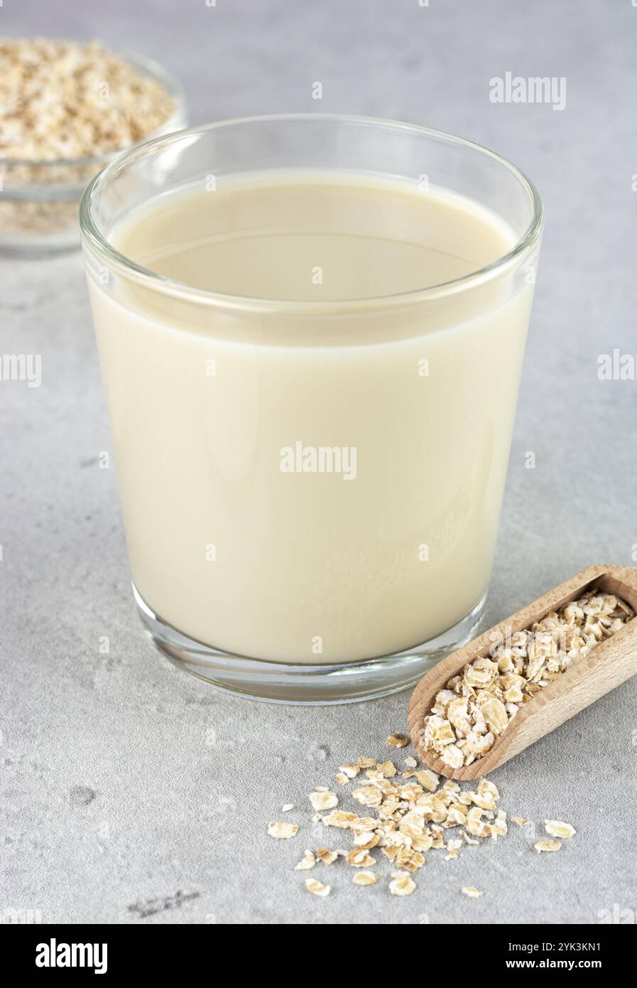 A glass of oat milk and oatmeal on a gray background. Copy space. The ...