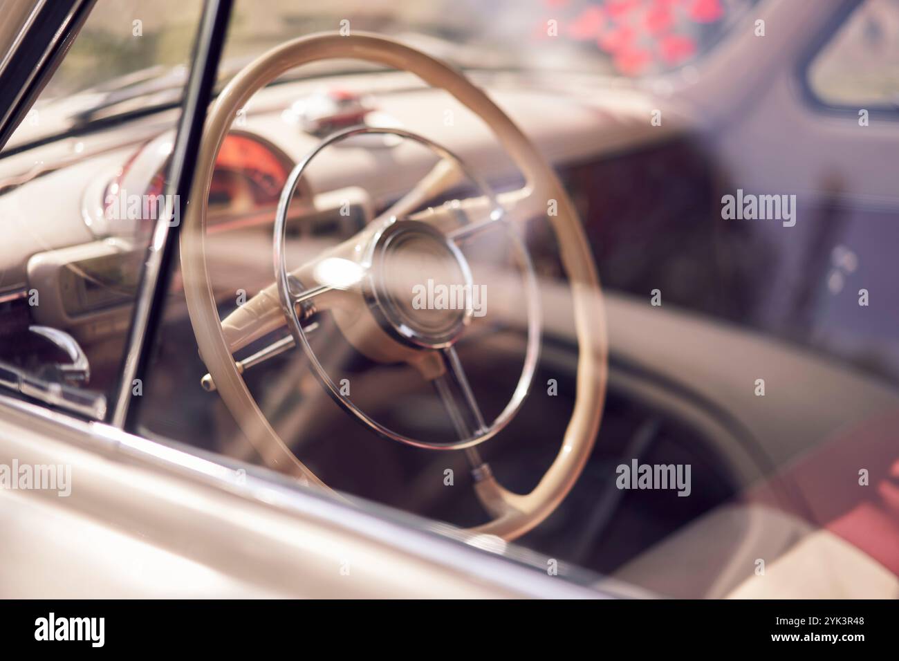 A vintage cars steering wheel and classic dashboard can be seen through ...