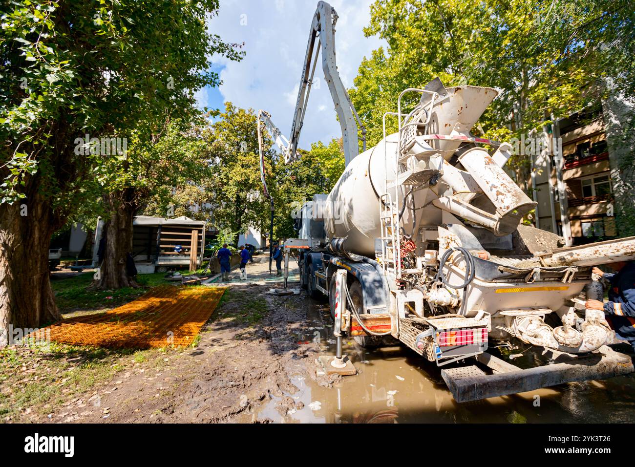 Pouring fresh concrete from mixer truck over ramp to another that has a ...