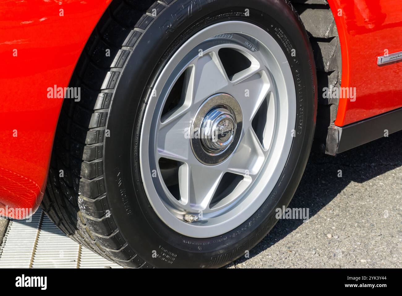 Close up detail of a magnesium knockoff alloy wheel on a rosso corsa ...
