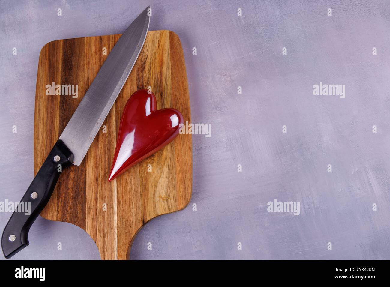 Top-down view of a red porcelain heart on a board with a knife ...