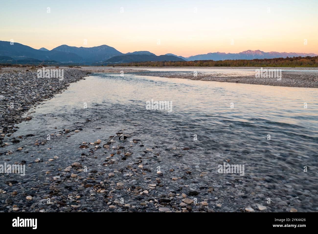 The Tagliamento river riverbed at dusk with, rocks and pebbles and sun ...