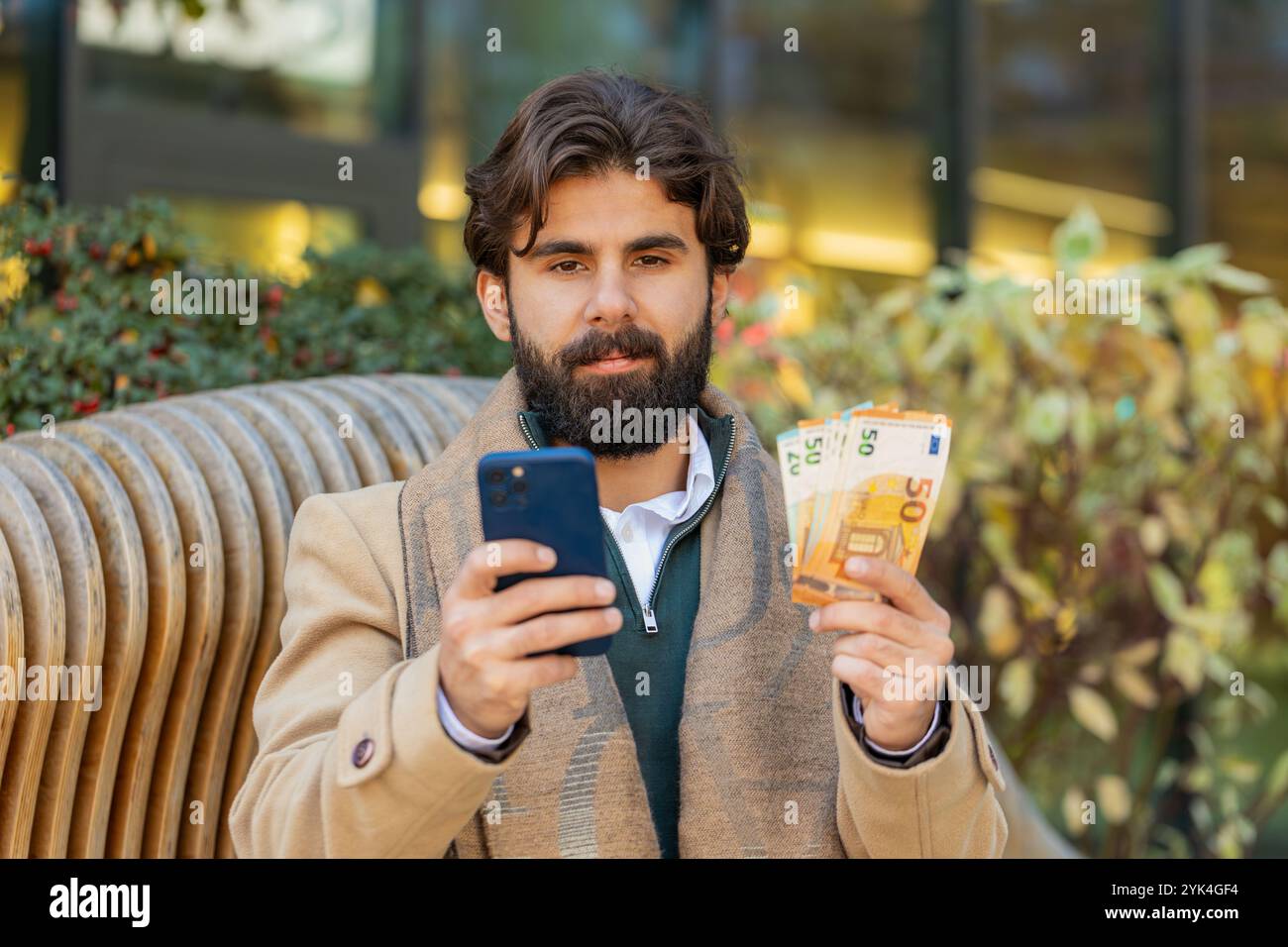 Happy rich Indian businessman tourist using smartphone and counting ...