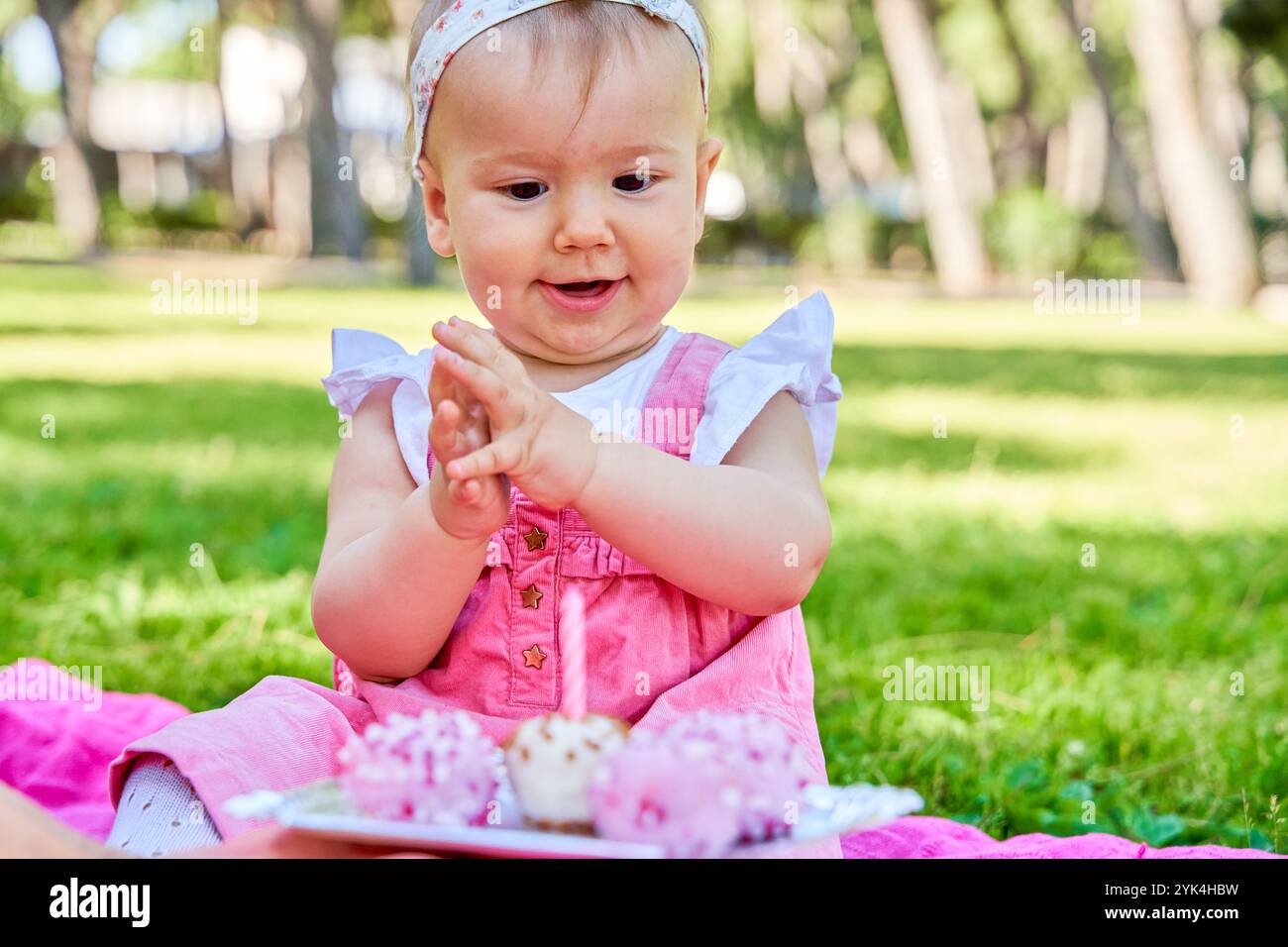 Baby girl in a pink dress clapping with excitement while celebrating ...