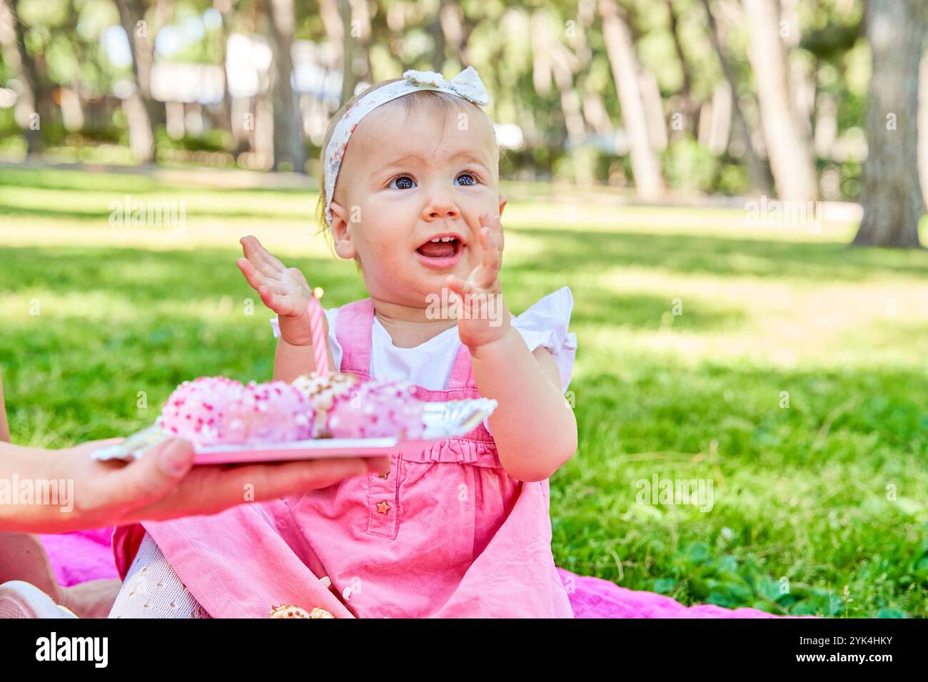 Baby girl in a pink dress clapping with excitement while celebrating ...