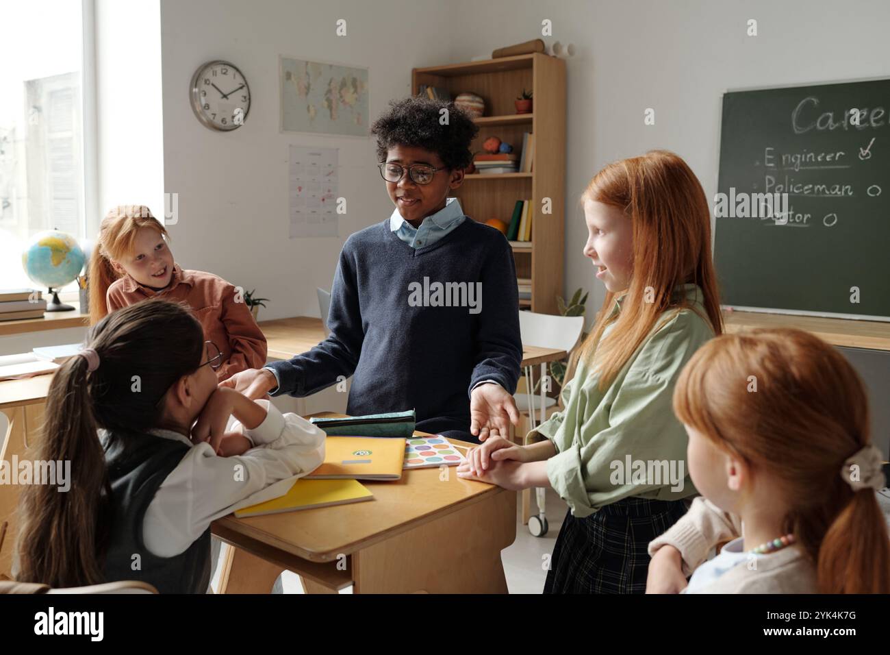 Cute African American schoolboy looking at one of several classmates ...