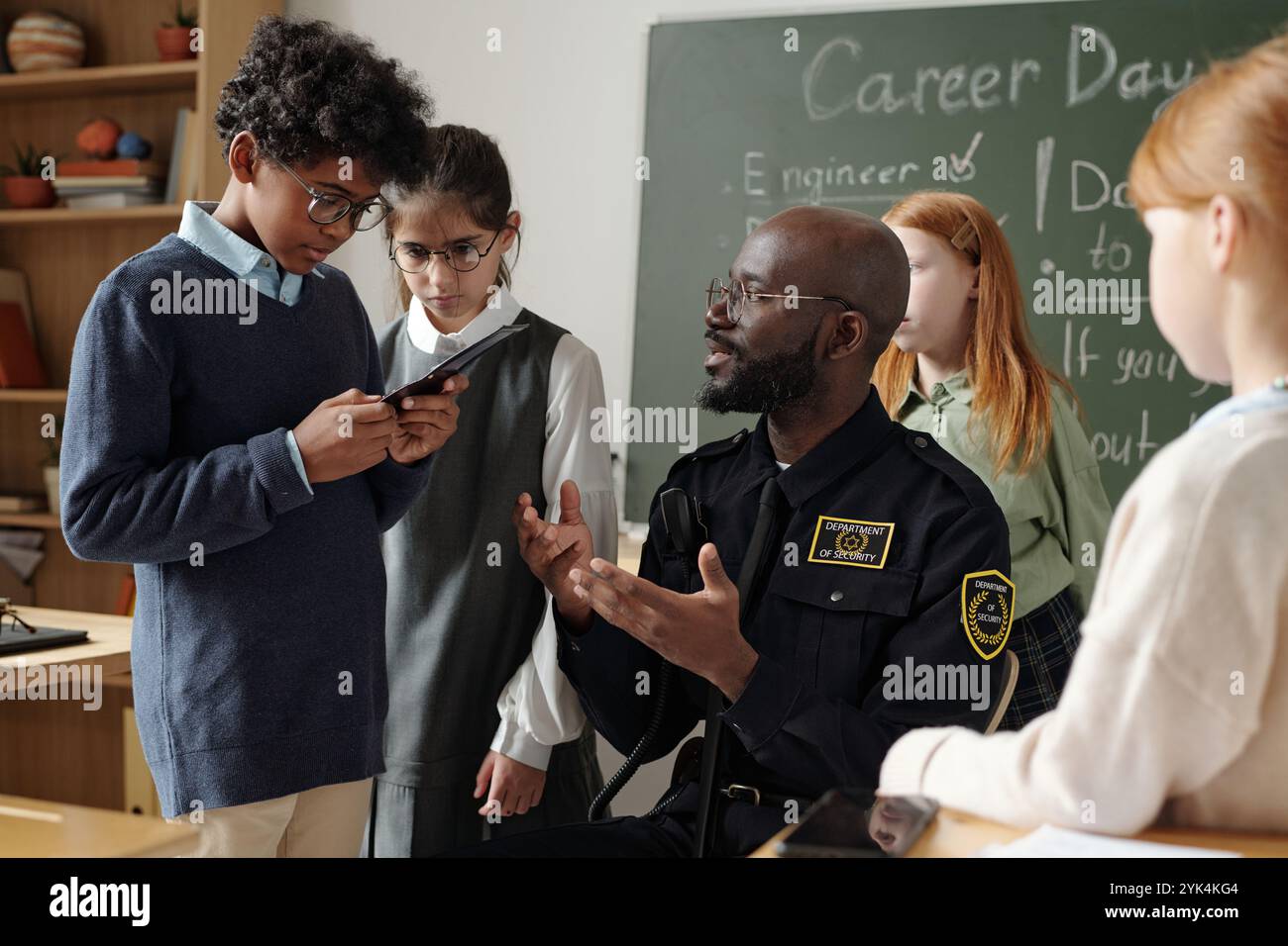 Cute primary school pupil looking at badge of policeman while standing ...