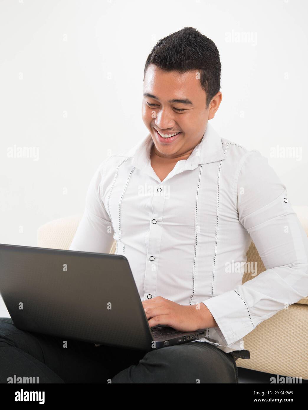 Wireless online Southeast Asian man sitting on floor, browsing internet. Copyright: xZoonar.com ...