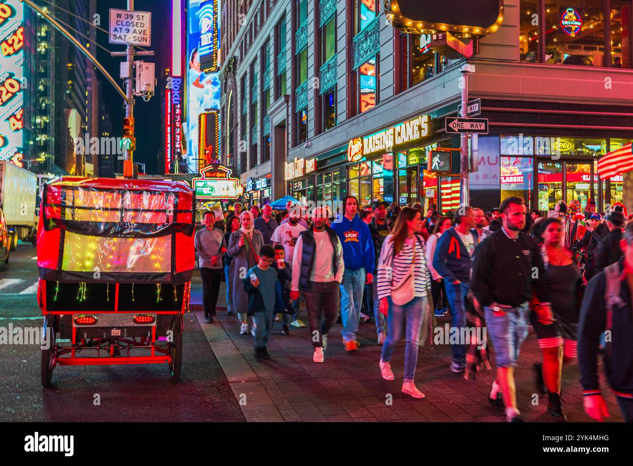 Colorful night street scene in Times Square with lit pedicab and crowd ...