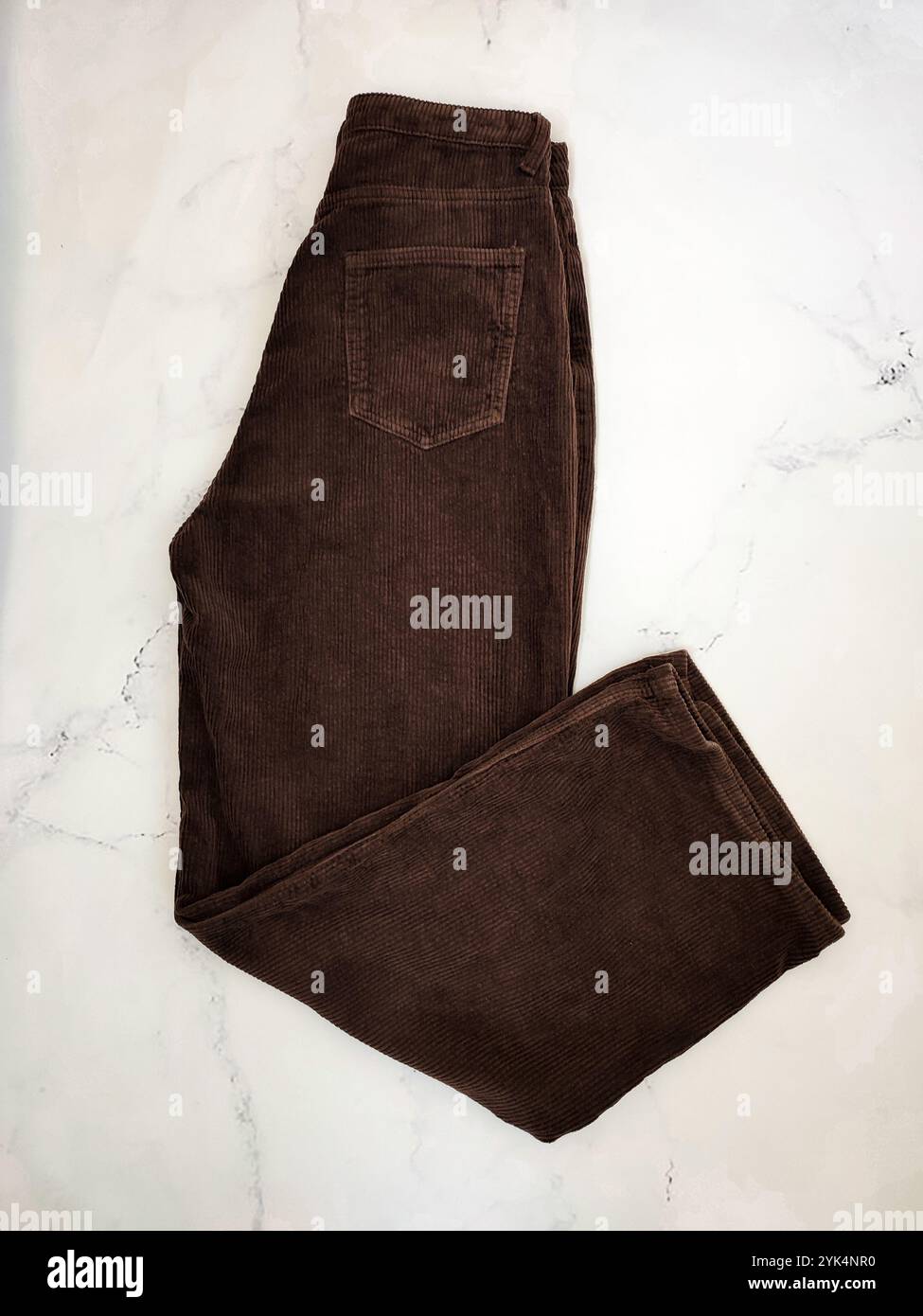 Brown corduroy pants side flat lay at white marble background top view ...