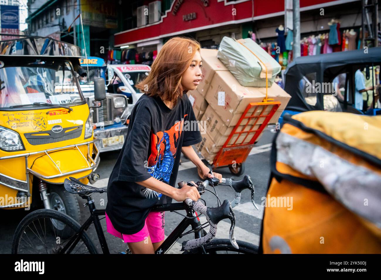 A beautiful young Filipino girl makes her way along a busy market ...