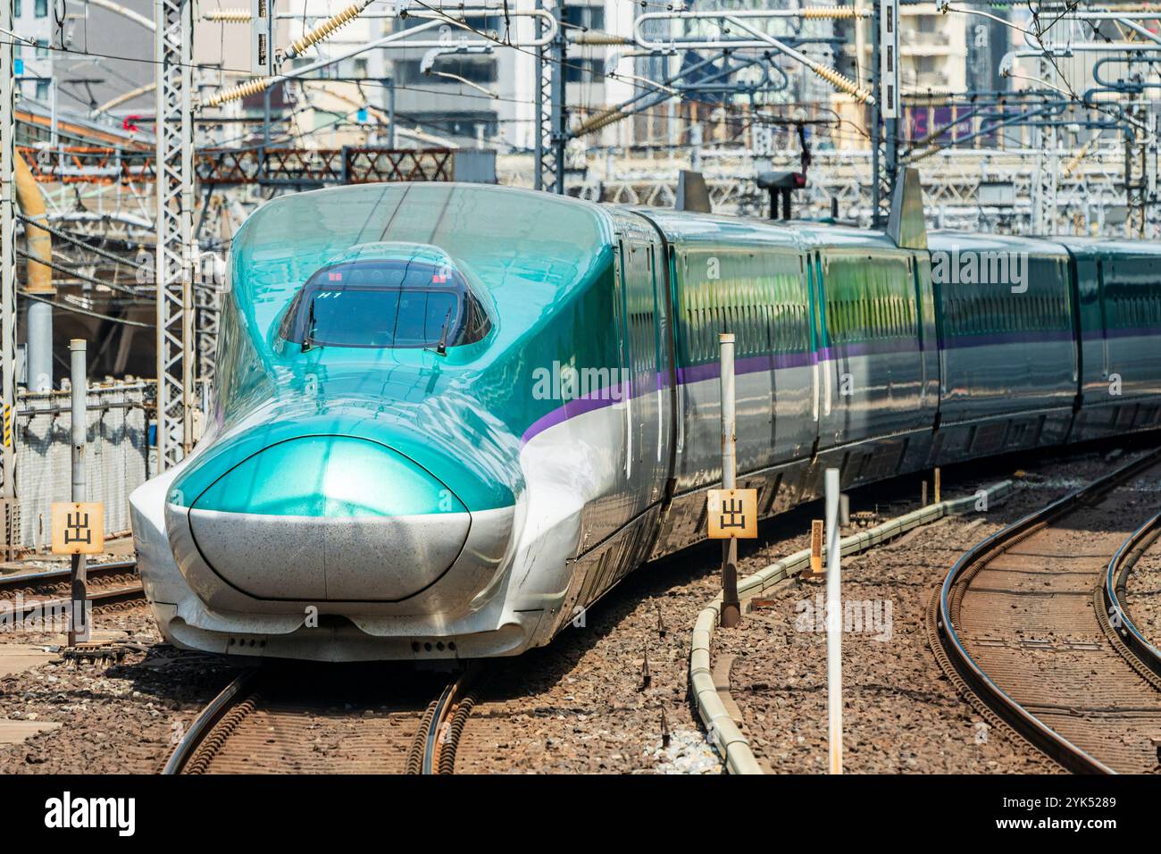 Japanese E5 series Shinkansen bullet train approaching Tokyo station. Compressed perspective ...