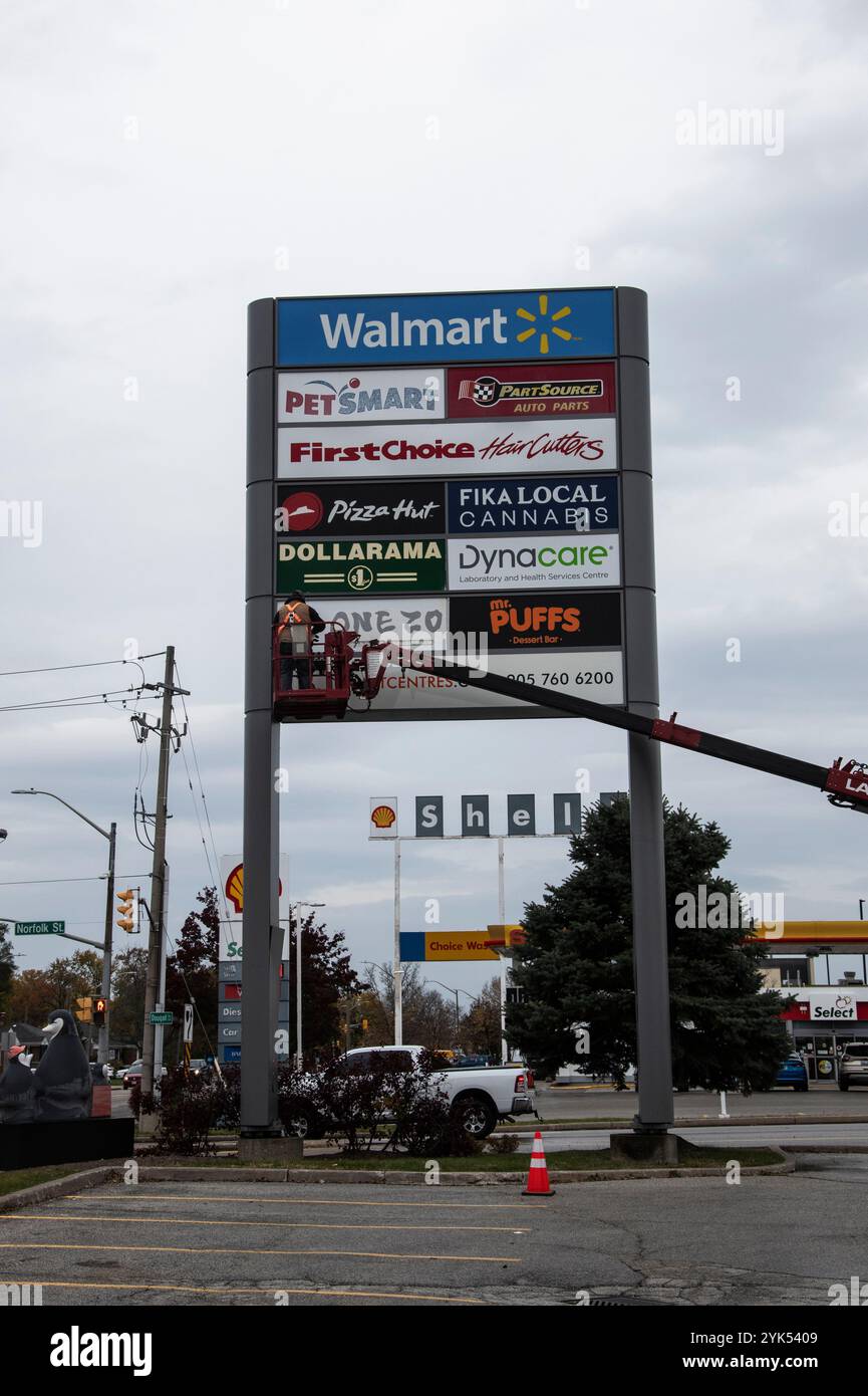Worker in a bucket lift crane changing signs at Smart Centres shopping ...