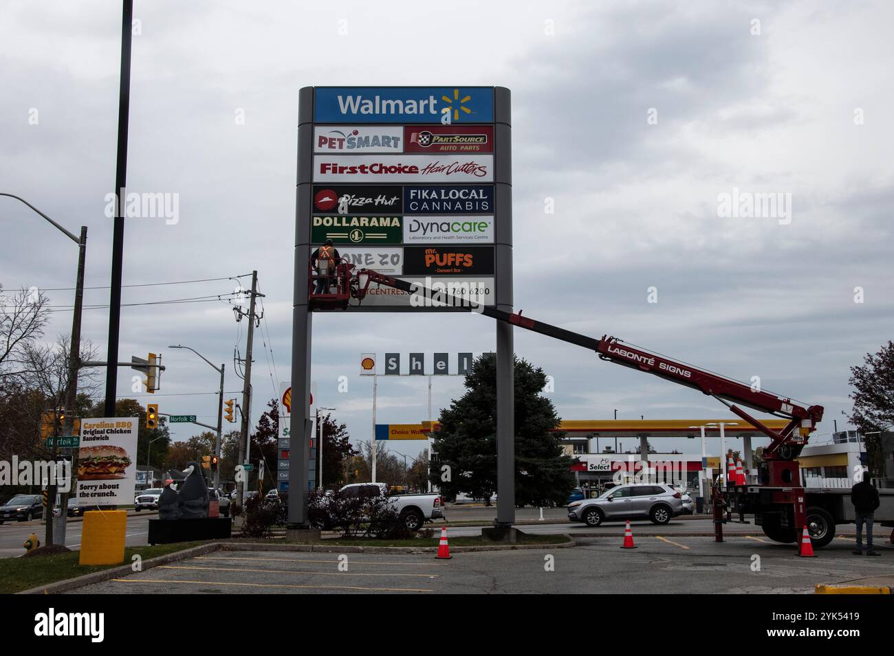 Worker in a bucket lift crane changing signs at Smart Centres shopping ...