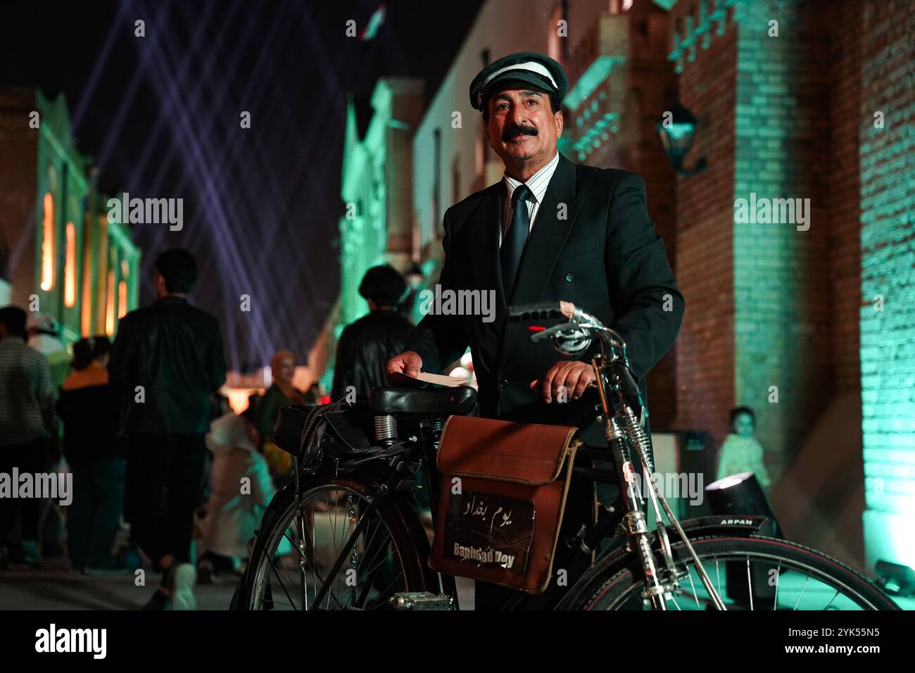 A man dressed as a postman stands with his bicycle during the Baghdad ...