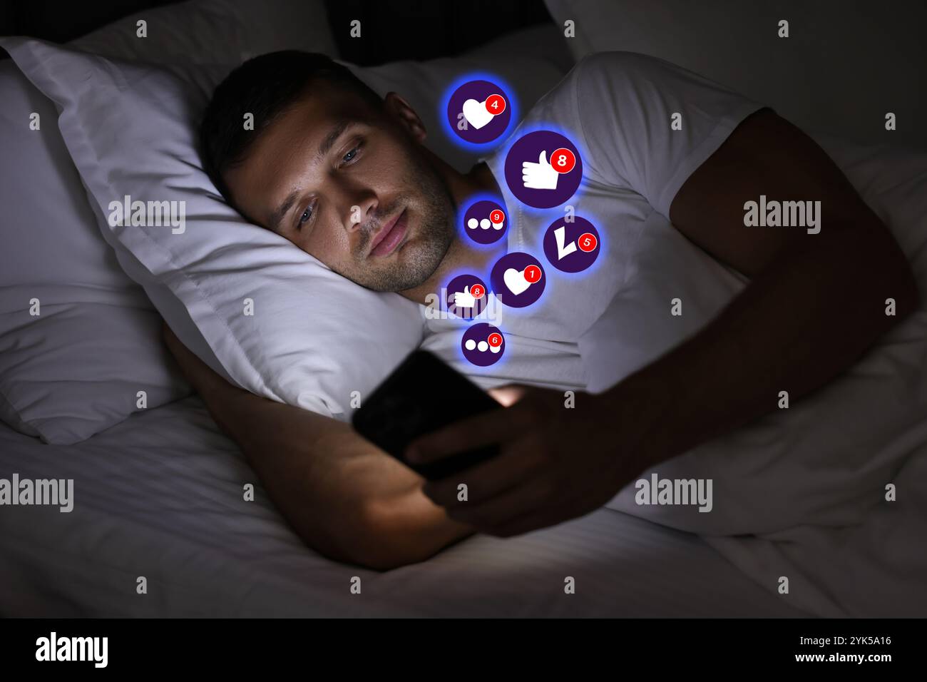 Man using mobile phone in bed at night. Different notification signs ...