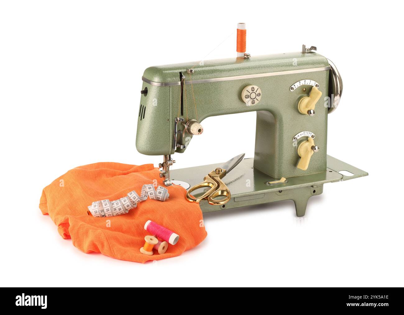 Sewing machine with orange fabric, measuring tape, scissors and spools ...