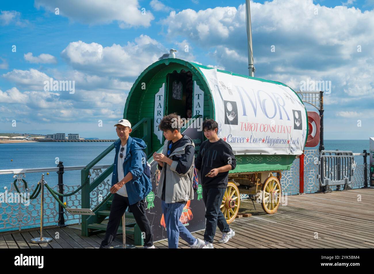 Three adolescent boys walking past a gypsy fortune teller caravan on ...
