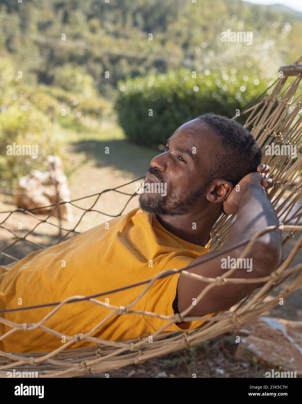 African American man enjoying nature, resting on a hammock during ...