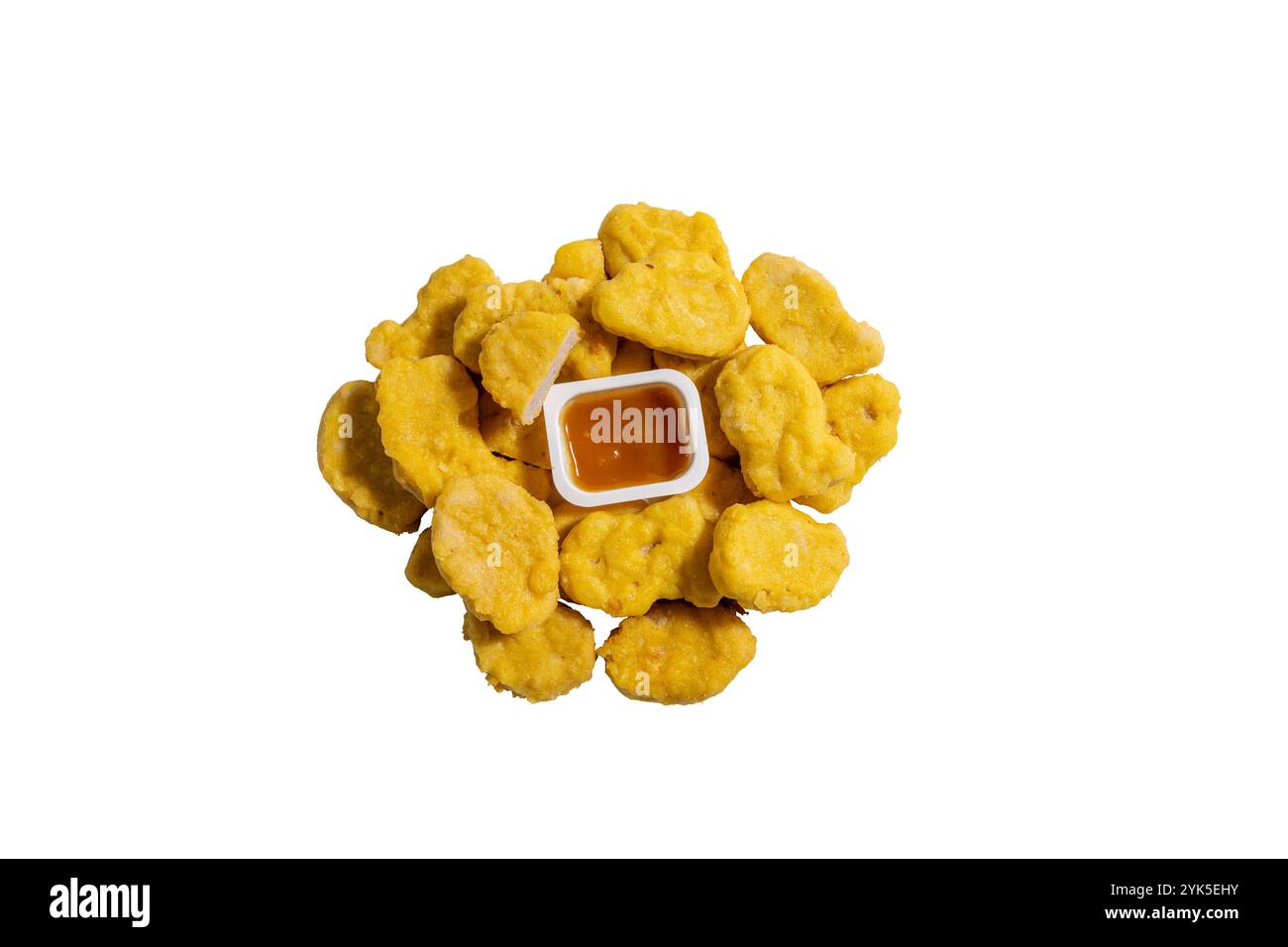 A pile of yellow chicken nuggets with a small container of sauce in the ...