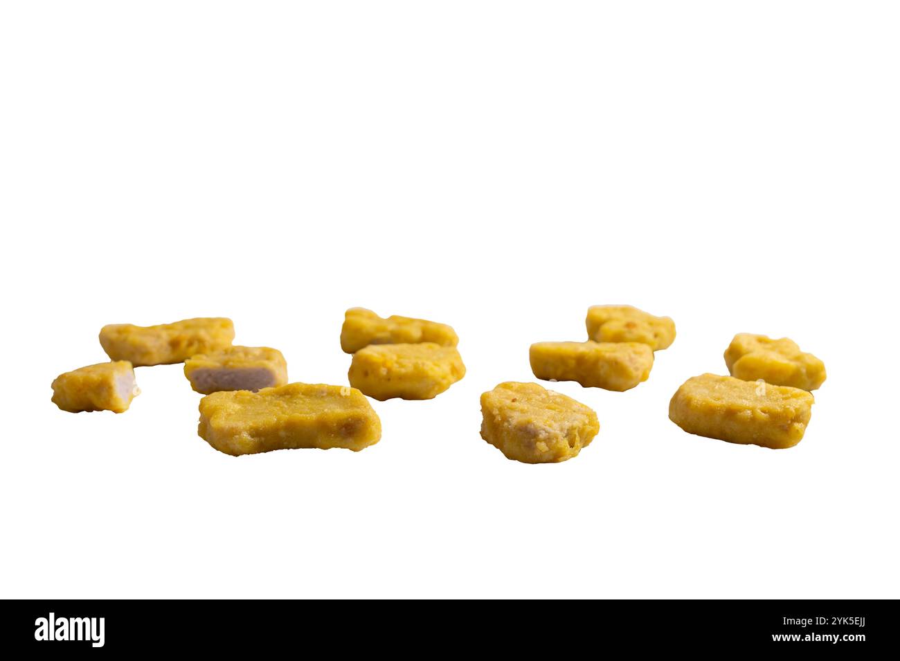 A pile of yellow chicken nuggets on a white background. The nuggets are ...