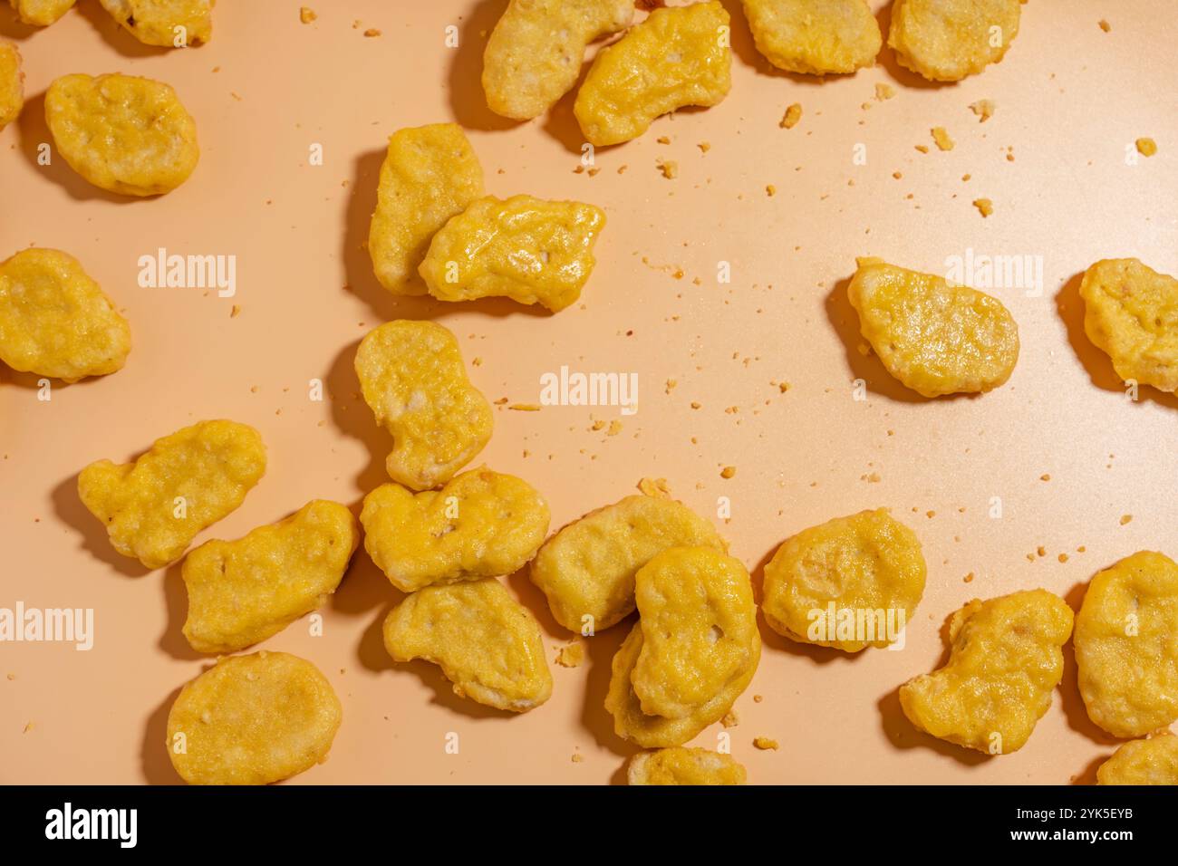 Chicken nuggets with crumbs are scattered on the table. The nuggets are ...